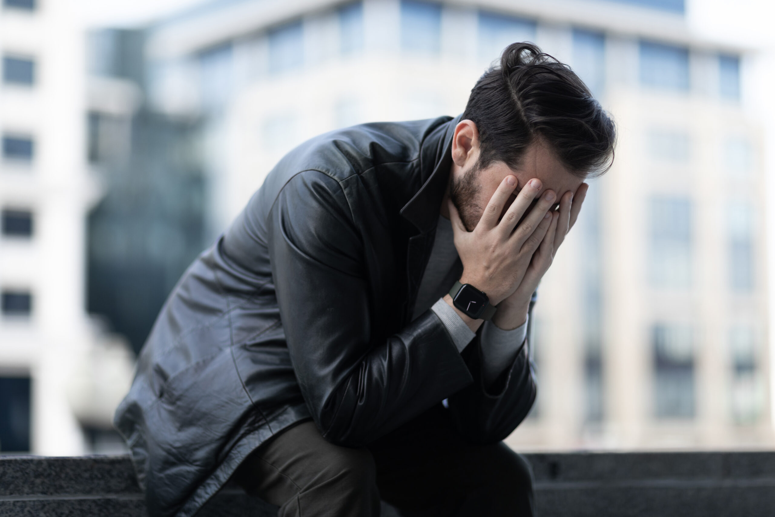 distressed middle-aged man crying with his eyes closed while sitting on ...